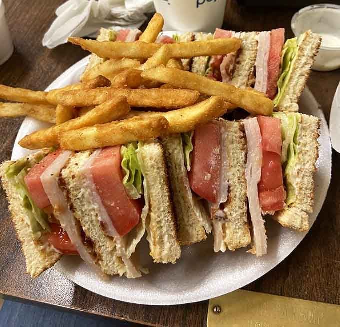 The club sandwich cut into perfect triangles because some traditions exist for good reason, fries included for moral support.