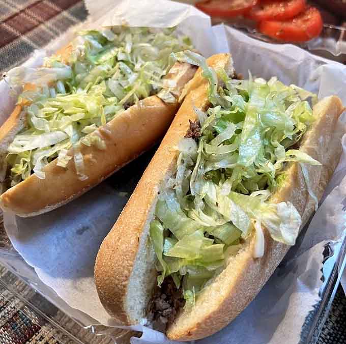 A proper cheesesteak nestled in a soft roll with shredded lettuce cascading over the top like edible confetti.