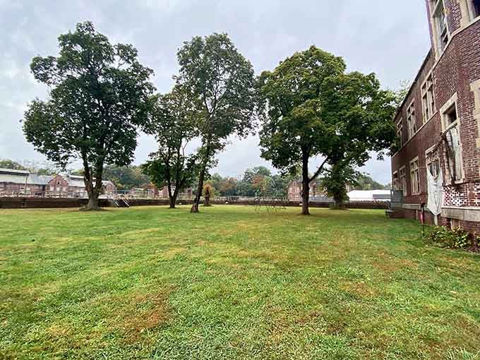 Mature trees frame the campus, offering peaceful contrast to the buildings' troubled past and present purpose.