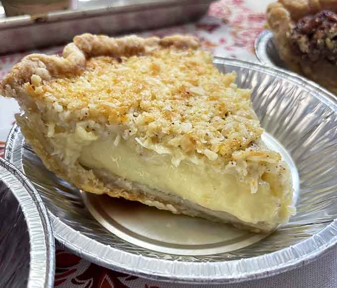 Coconut custard pie topped with toasted flakes, delivering tropical comfort in every creamy bite you take.