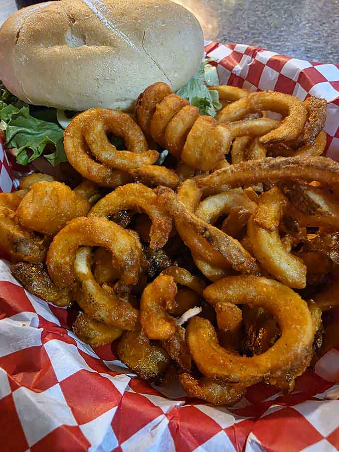 Onion rings piled high next to a burger, because sometimes you need circles of fried joy with lunch.