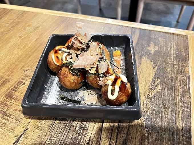 Takoyaki topped with dancing bonito flakes, because your appetizer should always put on a show before disappearing.