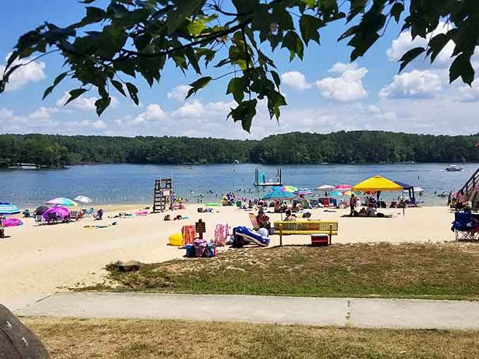 Colorful umbrellas dot the sand as families claim their spots in this lakeside summer paradise.