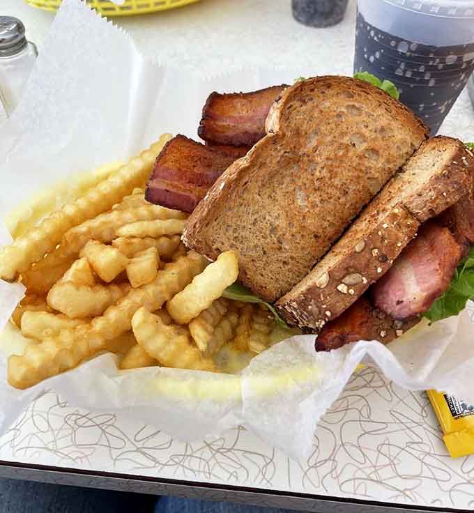 Thick-cut bacon towers between toasted bread, creating the BLT of your childhood dreams with waffle fries as backup.