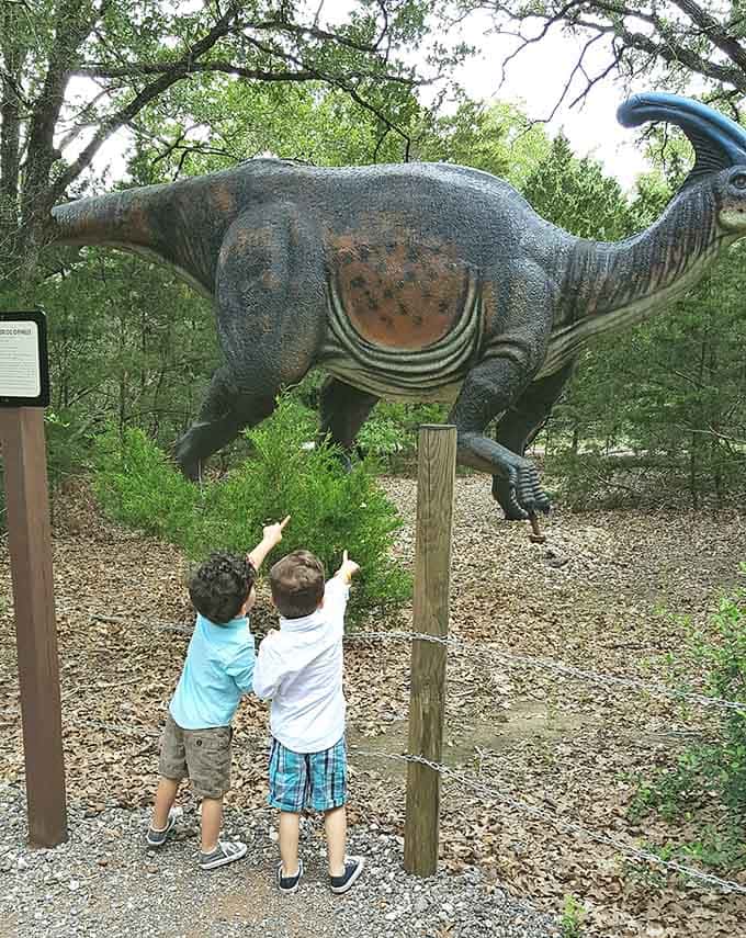 Wonder and awe captured perfectly as two young explorers reach toward their towering prehistoric discovery together.