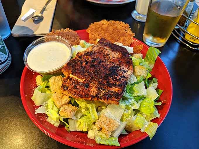 Fresh salad topped with perfectly seasoned grilled chicken and crunchy sides at The Filling Station makes a satisfying, flavorful, and inviting meal.