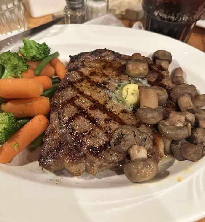 A perfectly grilled ribeye with mushrooms that could make a vegetarian reconsider their life choices, just temporarily.