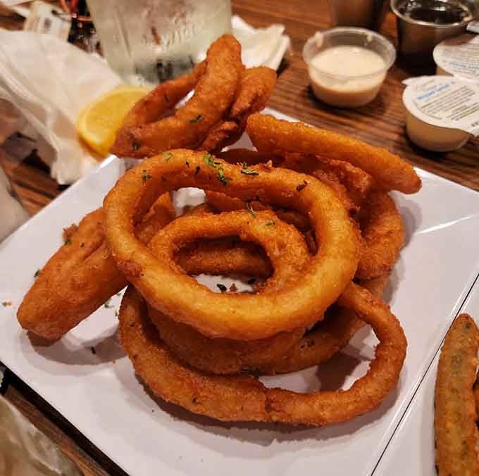 Onion rings stacked like edible architecture, crispy enough to hear across the dining room.