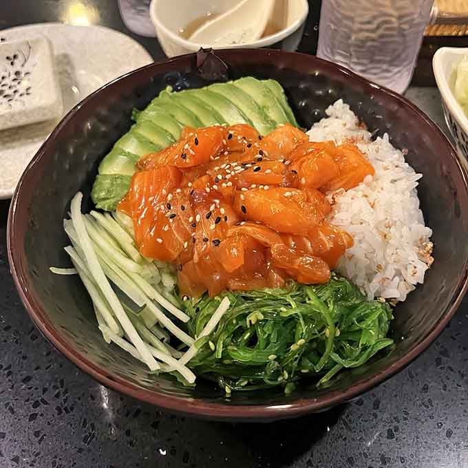 Fresh salmon glistening over rice with avocado and seaweed creates a bowl of pure happiness and healthy fats.