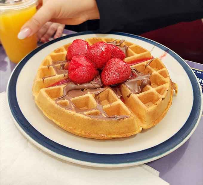 Fresh strawberries crowning a golden waffle with Nutella, because sometimes breakfast should feel like winning the lottery.