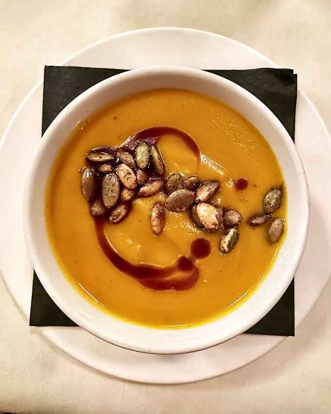 Silky pumpkin soup with toasted pepitas and that artistic drizzle makes you wonder why anyone settles for canned anything.