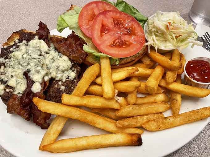 Blue cheese crumbles melting over a juicy burger with crispy bacon is happiness on a plate.