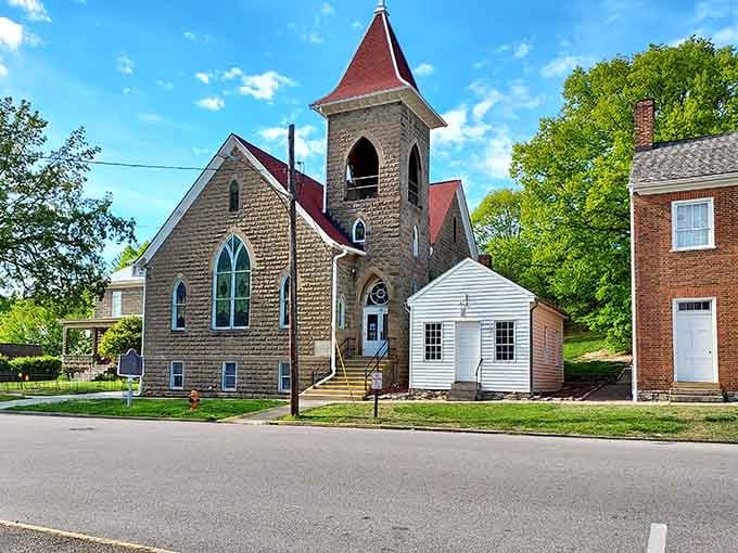 This stone church's red steeple reaches skyward, anchoring the community with grace and timeless beauty that inspires reverence.