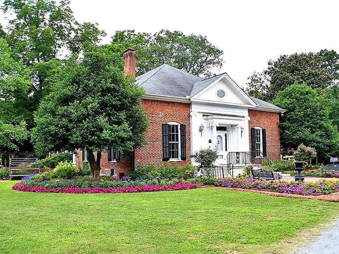 This red-brick gem is dressed to impress with a white portico and flower beds bursting with vibrant, purple personality.