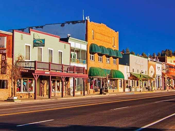 Old West facades painted in cheerful colors bring character to streets where autumn leaves frame distant peaks beautifully.