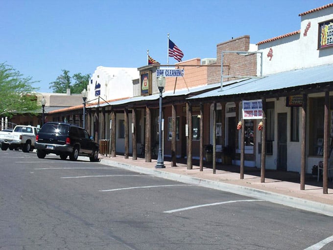 Covered wooden sidewalks provide shade along this quiet street where the American flag waves proudly overhead.