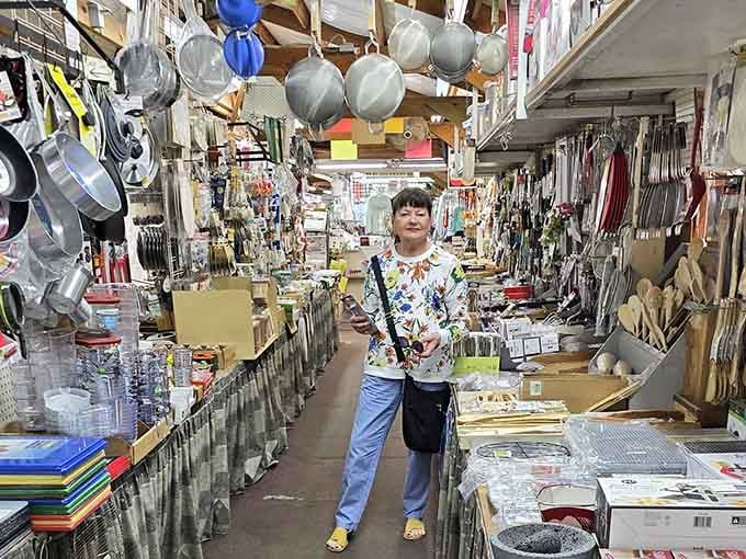 Surrounded by kitchen gadgets hanging overhead, this happy shopper found her paradise among the endless aisles.
