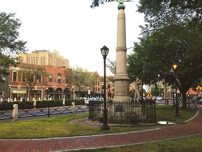 The town monument stands sentinel over brick pathways where generations have strolled, debated, and fallen in love under these trees.