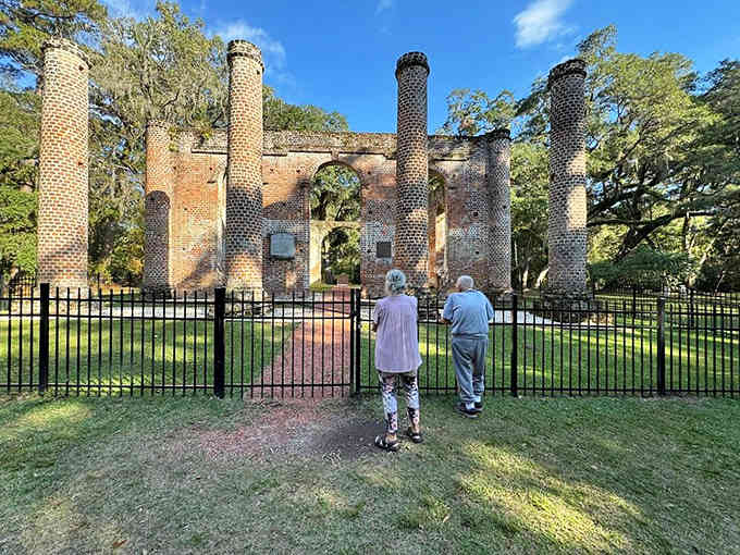 Two visitors stand at the gate, contemplating walls that survived fire twice and now stand as beautiful testimony to resilience.