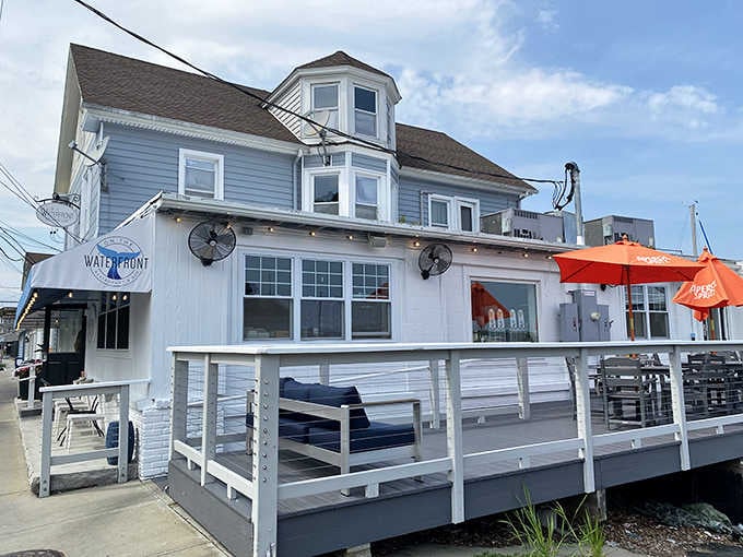 Bright orange umbrellas pop against white railings, creating a cheerful waterfront scene that practically demands a visit.