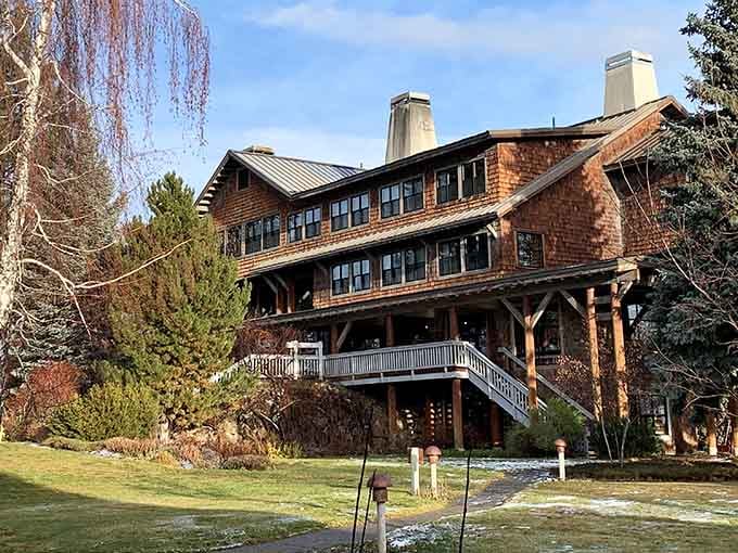 Massive timber beams and multiple chimneys showcase classic lodge architecture, standing proud against evergreens like a timeless monument.
