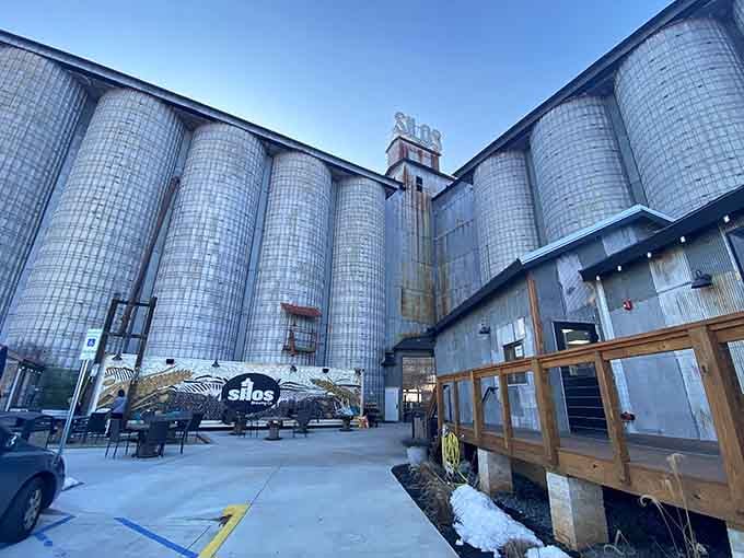 Towering grain silos create a dramatic backdrop for this brewery where industrial heritage meets modern craft beer culture perfectly.
