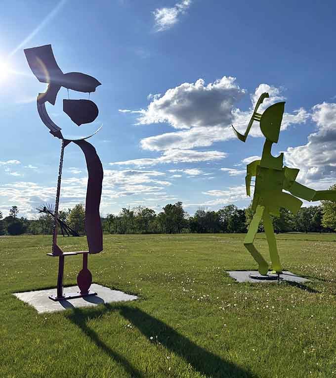 The purple and yellow sculptures cast dramatic shadows, creating their own silent movie on the grass below.