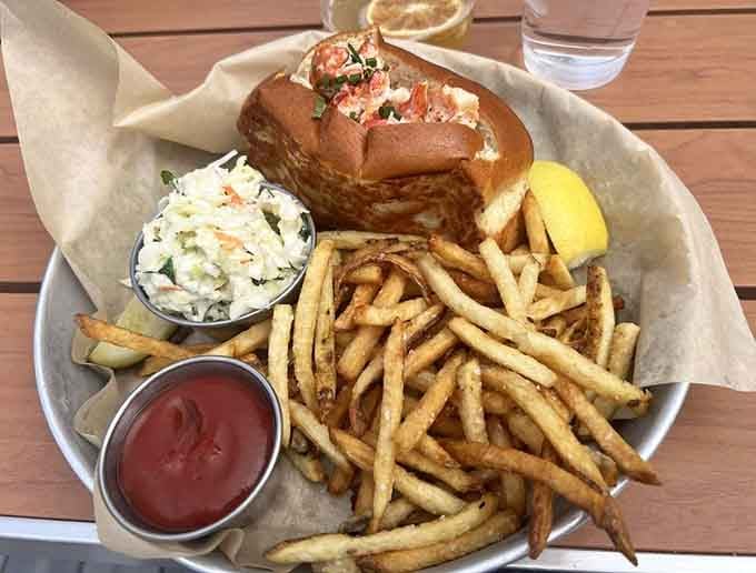 A lobster roll overflowing with sweet meat, crispy fries piled high, and coleslaw that actually looks worth eating too.