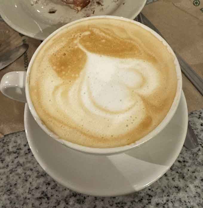 That swirled latte art sitting in a proper cup means someone here takes their coffee as seriously as their croissants.