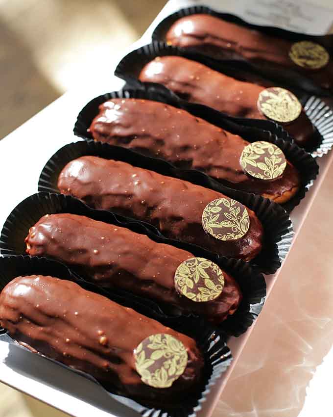 Chocolate eclairs lined up like soldiers, each one a crispy, creamy testament to French pastry perfection done right.