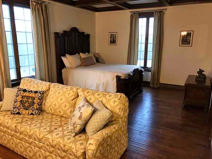 Dark wood floors and tall windows create a bedroom suite where modern comfort meets timeless elegance.