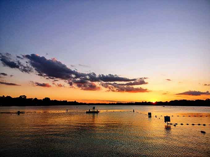 Spectacular sunset transforms ordinary lake water into liquid gold, reminding everyone why they chose this over Netflix tonight.