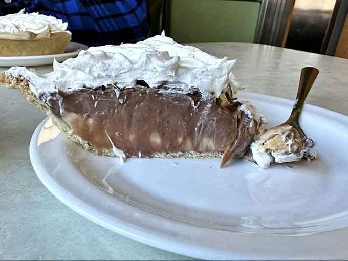 Peanut butter chocolate pie with meringue piled high enough to require architectural planning before each bite.