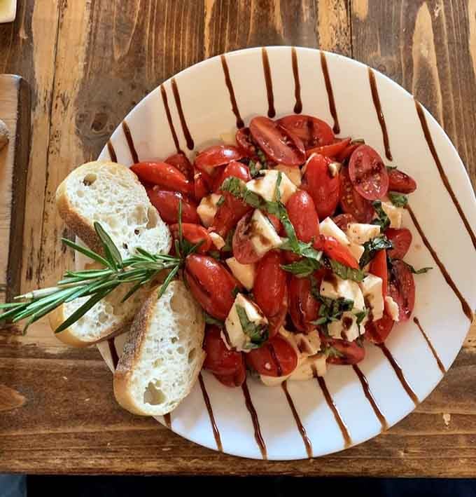 Fresh mozzarella, ripe tomatoes, and basil arranged like someone actually cares about your lunch experience and Instagram feed.