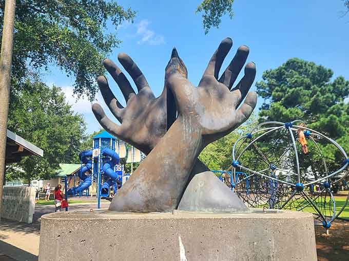 These oversized bronze hands reaching skyward add an unexpected artistic touch to this family-friendly community gathering spot.