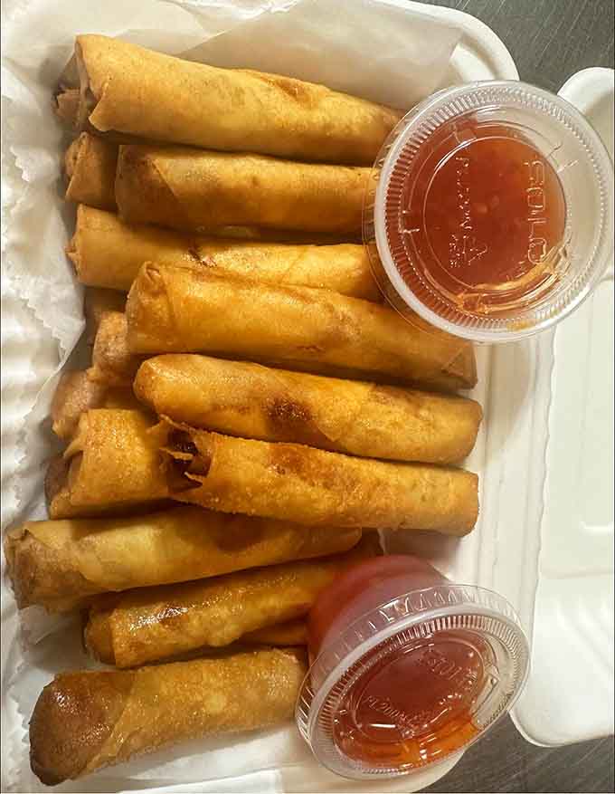 Golden-fried lumpia lined up like crispy little flavor torpedoes, complete with dipping sauce for the perfect finishing touch.