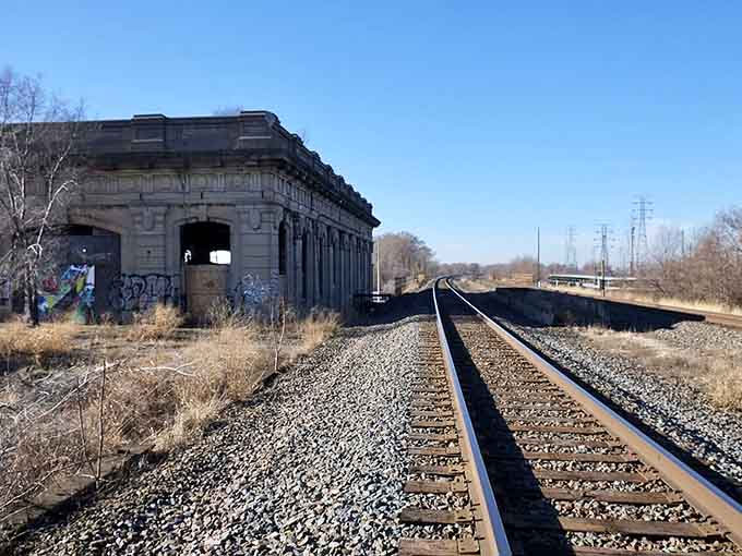 The tracks still carry trains, but the station that once greeted them stands empty and watching.
