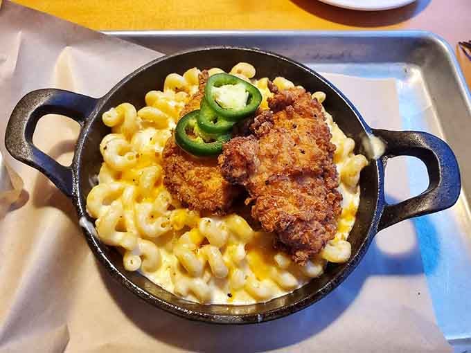 Crispy fried chicken nestled into creamy mac and cheese in a cast iron skillet, comfort food's greatest power couple.