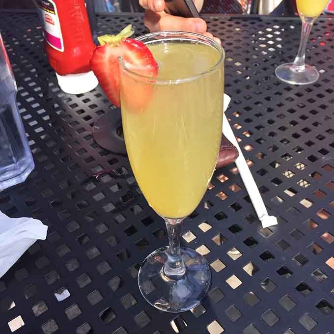 A mimosa garnished with fresh strawberry says brunch isn't just a meal, it's a lifestyle choice worth celebrating.