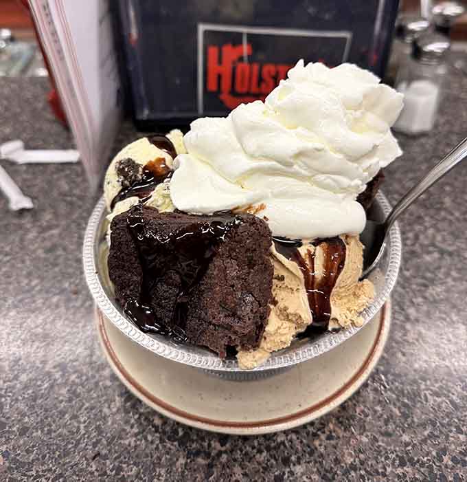 Brownie sundae architecture: layers of warm chocolate cake, ice cream, and whipped cream defying both gravity and restraint.