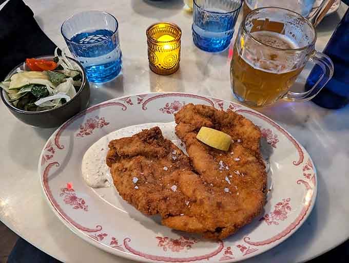 This golden schnitzel stretches across the plate like edible sunshine, crispy and ready for its close-up moment.