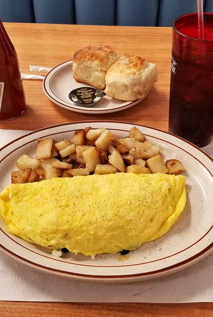 A fluffy omelet paired with seasoned hash browns and fresh biscuits makes choosing between sweet and savory completely unnecessary.