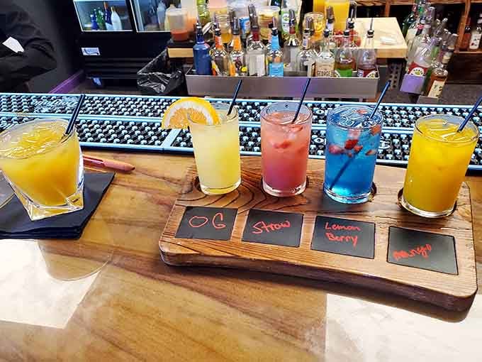 A cocktail flight presented on a wooden board lets you taste the rainbow without any childhood cereal involved.