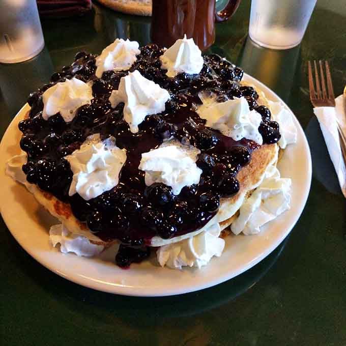 Blueberry pancakes topped with whipped cream that look like they're auditioning for a dessert magazine cover.