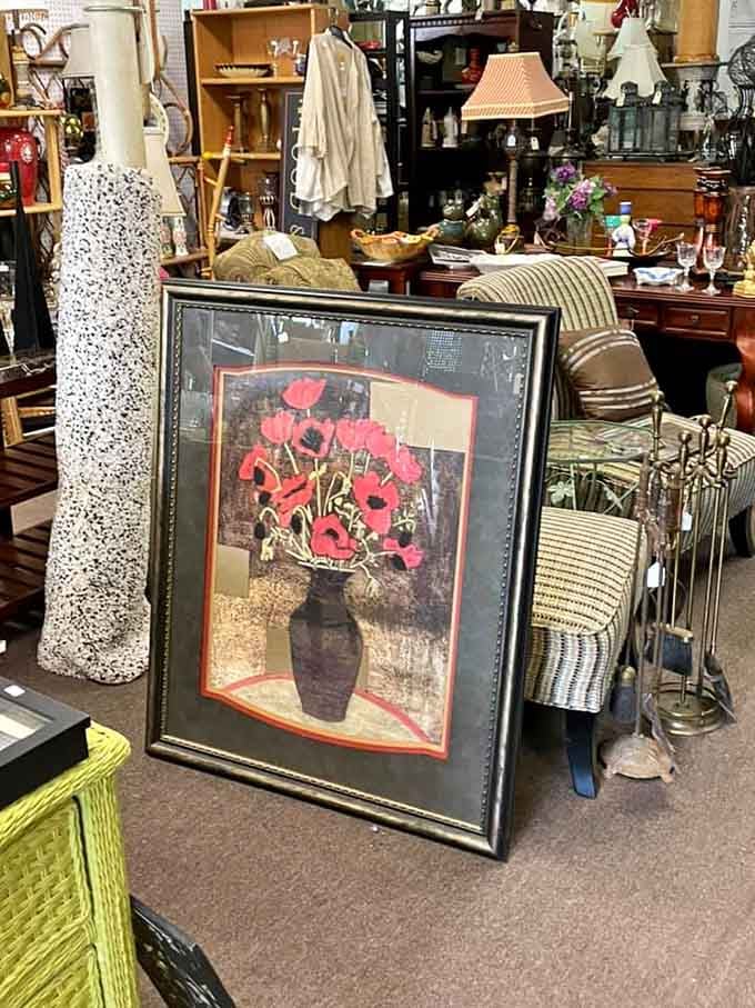 Framed floral art sits among vintage clothing and wooden furniture, creating an eclectic collector's paradise.