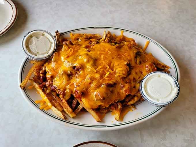 Chili cheese fries piled so high they require architectural support and possibly a forklift to finish them all.