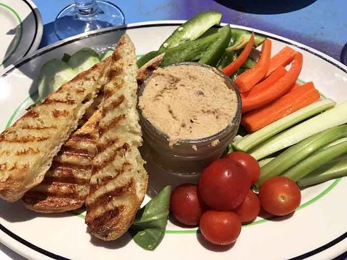 A hummus plate surrounded by fresh vegetables and grilled bread, proving healthy food can also be incredibly satisfying.