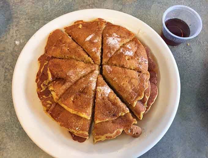 Pumpkin pancakes cut into perfect wedges with syrup waiting; autumn never looked or tasted quite this inviting before.