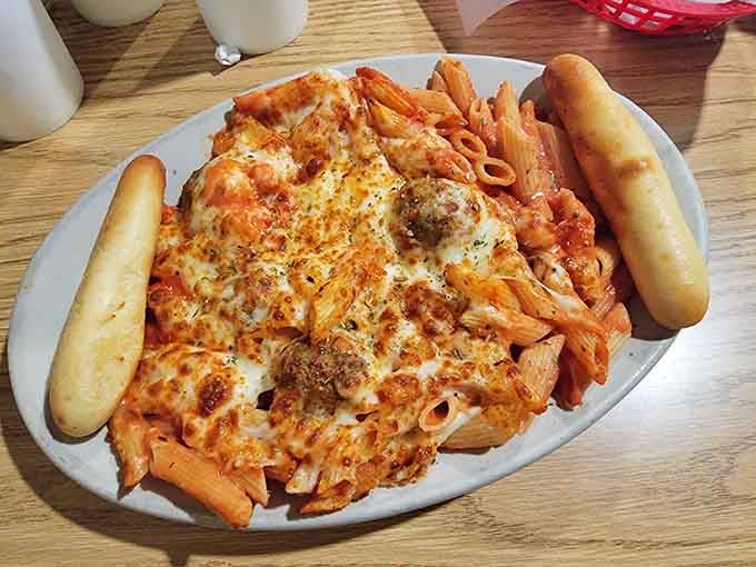 Baked penne topped with melted cheese and breadsticks that understand the assignment completely and beautifully.