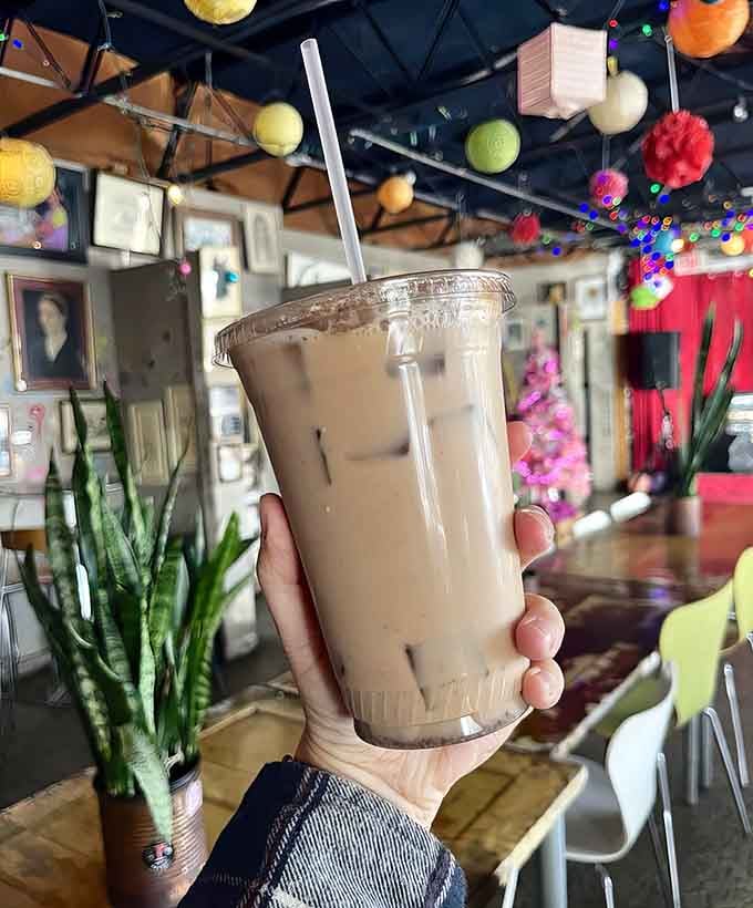 Iced masala chai served in a clear cup, showcasing those colorful lanterns overhead while delivering perfectly spiced refreshment below.